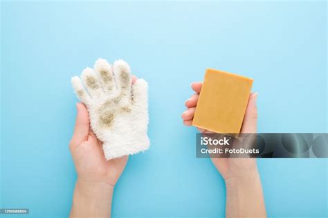 젊은 성인 여성 손은 더러운 아이 흰색 따뜻한 장갑과 밝은 파란색 테이블 배경에 가정용 비누를 들고 있습니다 파스텔 색상 근접
