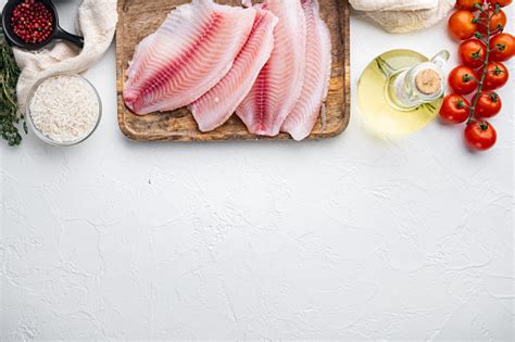 바스마티 쌀과 체리 토마토 재료가 있는 생 흰살 생선 틸라피아 흰색 배경 텍스트 복사 공간이 있는 상단 보기 건강한 식생활에