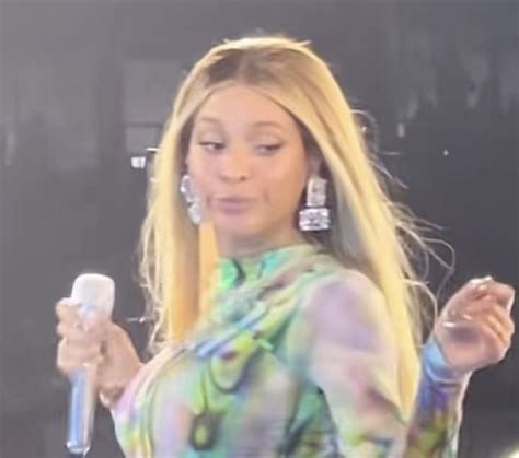 A Woman Holding A Cell Phone In Her Right Hand And Wearing Earrings On The Other