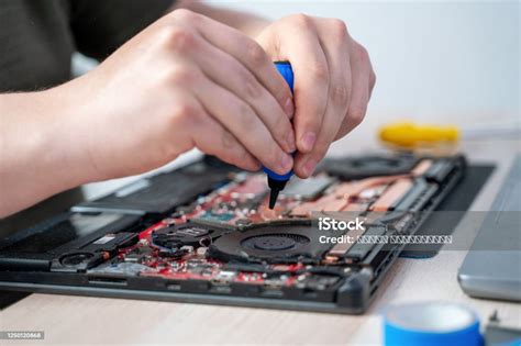 한 남자가 먼지를 불기위한 특별한 도구로 노트북을 청소합니다 노트북 냉각 시스템의 쿨러에 먼지 수리 및 서비스 노트북 및 Pc