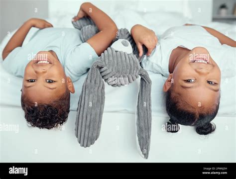 Adorable Little Sibling Brother And Sister Lying Upside Down Over The Edge Of A Bed With A