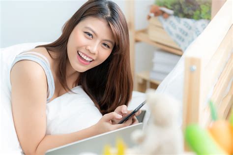 아름 다운 아시아 여자는 창 빛과 침실에서 스마트 폰과 아침 시간을 즐길 수 개념에 대한 스톡 사진 및 기타 이미지 개념