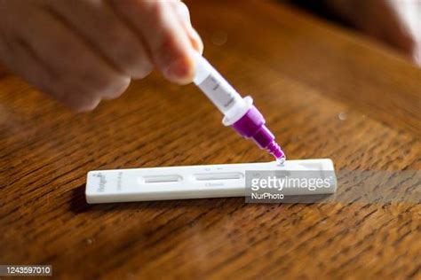 A Woman Drops A Swab Sample Into An Antigen Test Strip At Home In