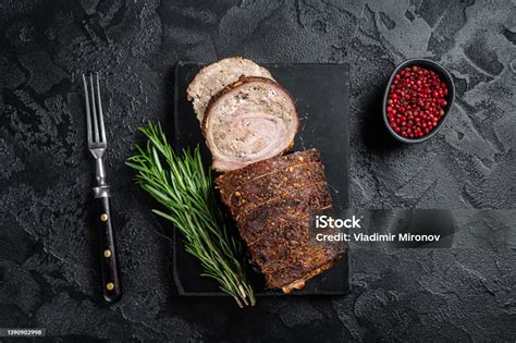 구운 돼지고기 룰라드 포르쉐타 허브가 있는 대리석 보드에 돼지고기 를 굴렸다 검은 색 배경 위쪽 보기 검은색에 대한 스톡 사진