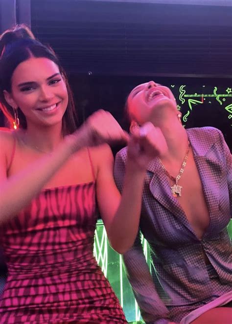 Two Women Sitting Next To Each Other In Front Of A Neon Sign And