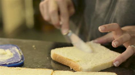 Premium Stock Video Young Woman Busy Buttering Bread To Make Sandwiches To Barbecue For Lunch