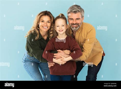 Middle Aged Father And Mother Embracing Little Daughter Blue