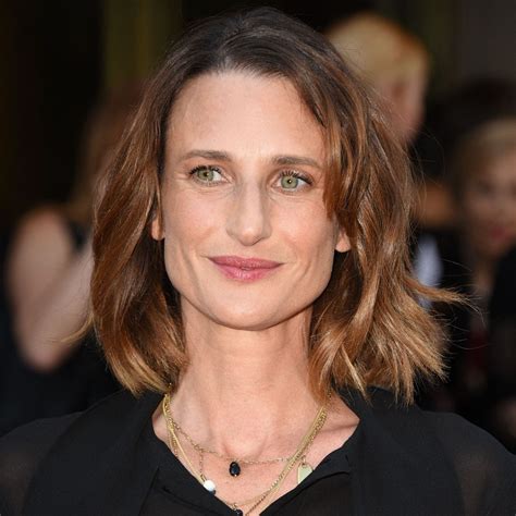 A Woman With Shoulder Length Hair Wearing A Black Shirt And Gold