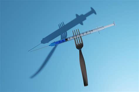 파란색 배경에 은색 포크로 찔러진 약이 든 의료용 주사기 식품 의약품의 개념과 알레르기 당뇨병 비만과 같은 식품과 의약품의