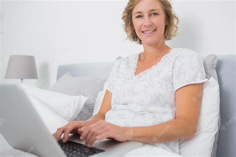 Premium Photo Cheerful Blonde Woman Sitting In Bed Using Laptop