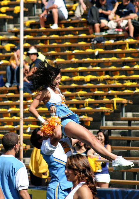Two Cheerleaders Are Performing Stunts In Front Of The Crowd