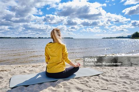 스포츠웨어를 입은 여성들은 연꽃 자세로 앉아 해변에서 요가 수업 중에 명상을합니다 요가 수업 호흡 명상 Ardha Padmasana 운동을하는 연습 웰빙 개념