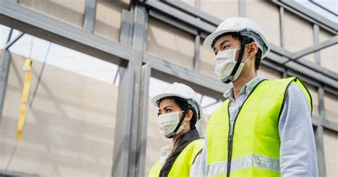 코로나19 또는 코로나바이러스 전염병으로 인해 건설 현장에서 보호 마스크를 착용한 아시아 노동자들 건물을 바라보는 남녀 엔지니어 건설 작업을 하고 프로젝트에 대해