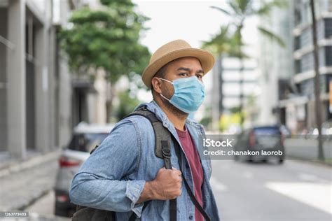 바이러스 안전 여행을 보호하기 위해 얼굴 마스크를 착용하고 도시 도시를 여행하는 젊은 아시아 배낭 여행자 가방에 대한 스톡 사진
