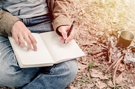 아시아 젊은 사람이 앉아 펜 들고 텐트 밖에 서에서 책에 추억을 기억 편지의 메모를 작성 숲에서 캠핑 하는 외로움 가격에 대한