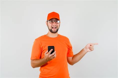 Free Photo Delivery Man Holding Mobile Phone And Pointing To The Side