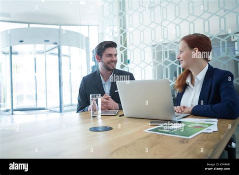 Business executives interacting while using laptop at desk Stock Photo - Alamy