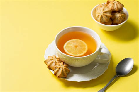 흰색 컵에 레몬과 노란색 배경에 흰색 세라믹 그릇에 양귀비 씨앗레몬 쿠키와 차 아침 식사 또는 간식의 개념 노랑에 대한 스톡