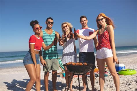 Premium Photo Group Of Friends Toasting Beer Bottles On The Beach