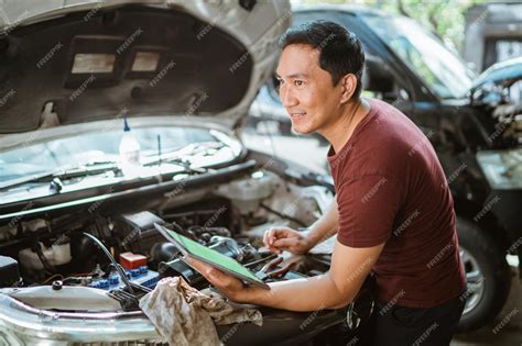 Premium Photo | Car mechanic using a tablet digital to checking up on car engines parts for ...