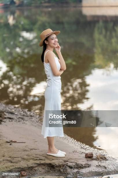 흰 드레스와 모자를 쓴 아시아 여성이 이른 아침 햇살을 받으며 매 핑 강가에서 휴식을 취하고 있습니다 30 34세에 대한 스톡 사진 및 기타 이미지 Istock