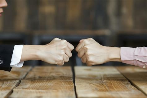 Two Hands Bumping Fists In Agreement Over Wooden Table Premium Ai