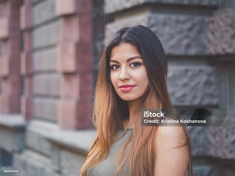 젊은 매력적인 여자의 미소와 함께 카메라에 보인다 동양 얼굴 갈색 눈 세련 된 얘기와 여자 긴 Haistyle 건축 배경 염색 스트리트 스타일 가죽에 대한 스톡 사진 및