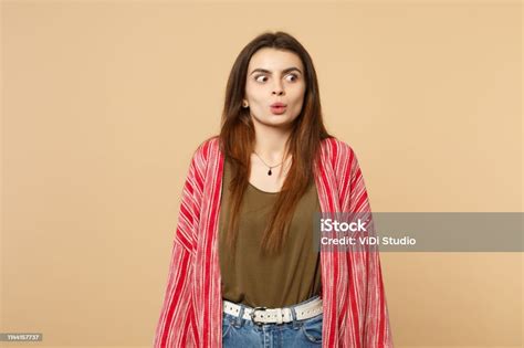 깜짝 놀란 젊은 여자의 초상화는 서 서 옆에 있는 파스텔 베이 지 벽 배경에 고립 된 스튜디오에서 사람들은 진심으로 감정 라이프