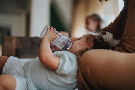 Mother And Daughter Bonding Time At Home With Bottle Feeding Stock