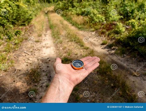 Compass In Hand At Road In The Forest Tourist Compass For Orientation On The Terrain Magnetic