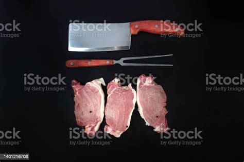 조미료 및기구 나이프 및 고기 포크로 구이를위한 생송아지 고기 필레 어두운 배경에 고기 칼이있는 안심 필레 미뇽 건강한 식생활에