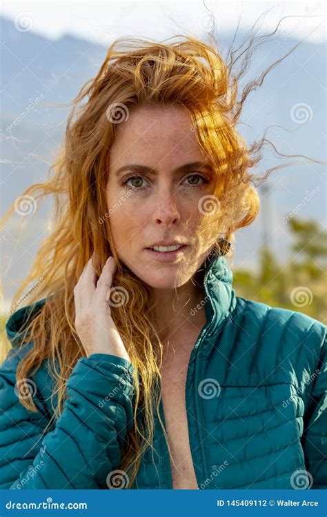 Redhead Model Posing Outdoors With Wind Turbines In The Background