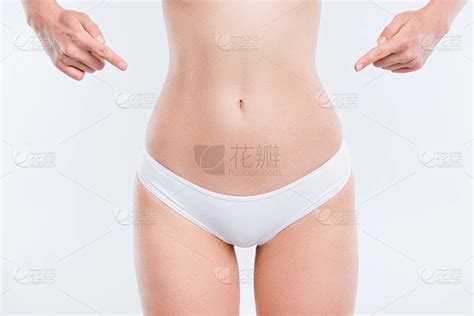 早期妊娠诊断裁剪的特写照片漂亮的瘦瘦运动女孩指着两个手指的腹部孤立在浅灰色的背景 花瓣网