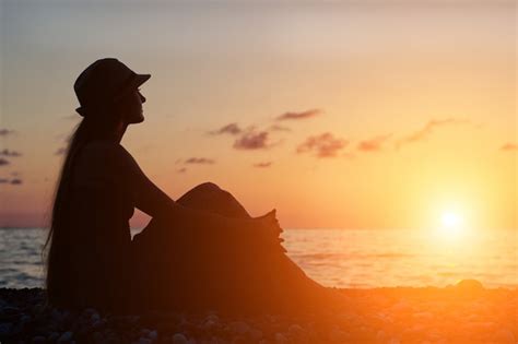 Premium Photo Girl Sitting On The Seashore At Sunset