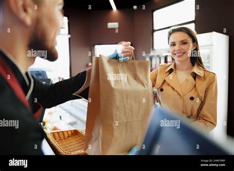 Shop Assistant Handling Shopping Bag To Female Customer In Grocery