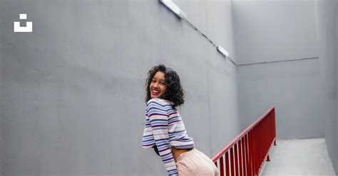 Une Femme Debout Sur Une Balustrade Rouge à Côté Dun Immeuble Photo
