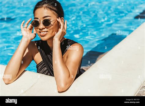 Asian Girl In Black Swimsuit And Sunglasses Relaxing In Swimming Pool