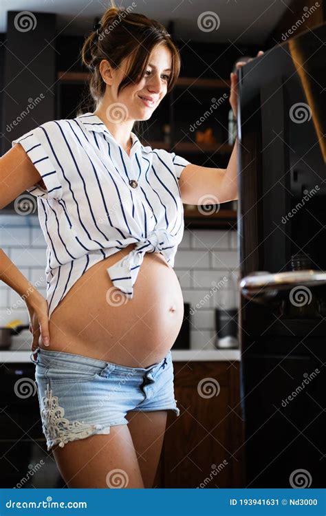 Young Hungry Pregnant Woman Looking For Food In Refrigerator Stock