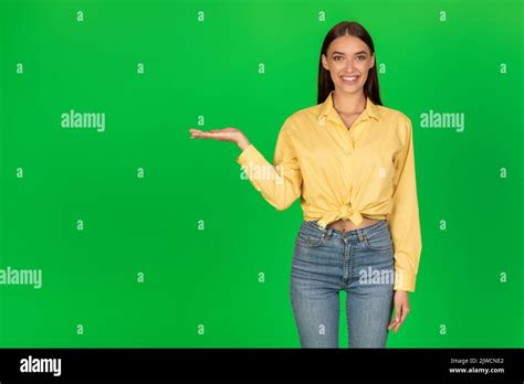 Happy Lady Holding Invisible Object On Hand Over Green Background Stock