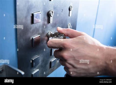 Close Up Of Human Hand Inserting And Turning The Key To Unlock Elevator