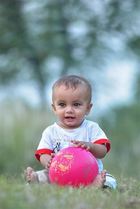 야외에서 핑크색 공을 가지고 노는 사랑스러운 아기 · 무료 스톡 사진