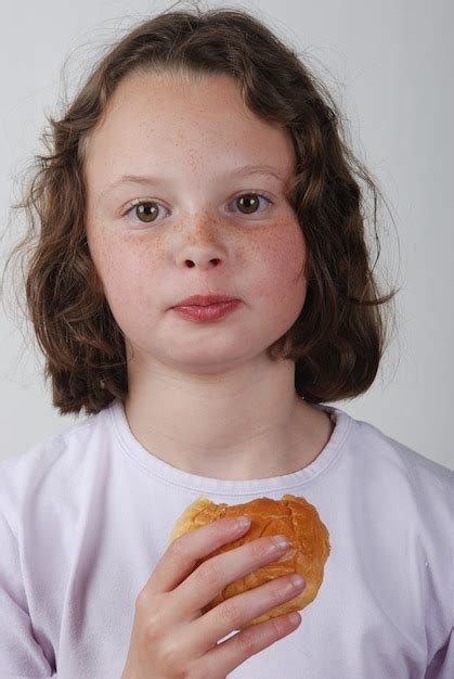 Premium Photo A Young Girl Eating A Bun