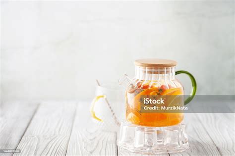 오렌지 레몬 사과 만다린 및 백리향의 뜨거운 감귤류 차를 곁들인 유리 주전자 어두운 나무 배경에 건강 음료 물에 대한 스톡 사진