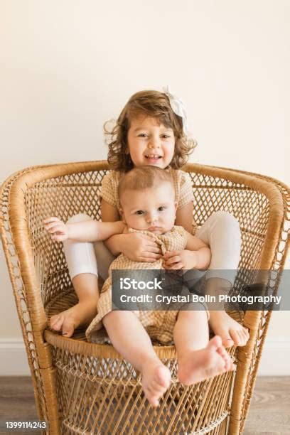 3 살짜리 유아 소녀가 5 개월 된 아기 동생을 안고 노란색 격자 무늬 의상을 입고 함께 앉아 있습니다 베이지에 대한 스톡 사진 및 기타 이미지 Istock
