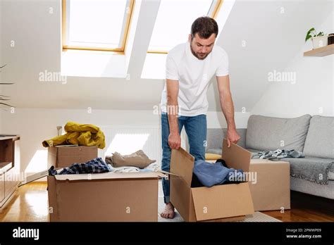 Man Packing His Old Apparel Into Cardboard Boxes At Home Reusing Second Hands Concept Stock