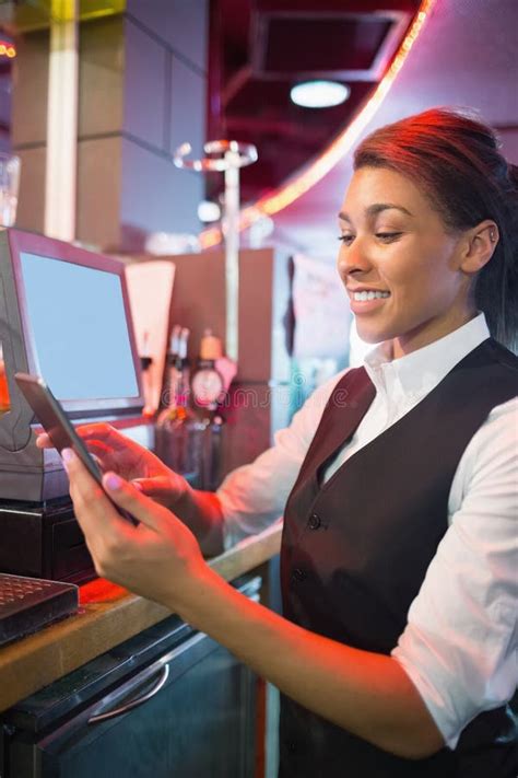 La Cameriera Al Banco Graziosa Che Usando Lo Schermo Attivabile Al