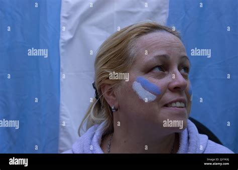 Blonde Woman With A Flag And Face Painted In The Colors Of Argentina