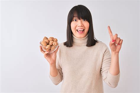 젊은 아름다운 중국 여자는 행복한 얼굴 번호 하나 손가락을 가리키는 아이디어 또는 질문으로 놀란 고립 된 흰색 배경을 통해