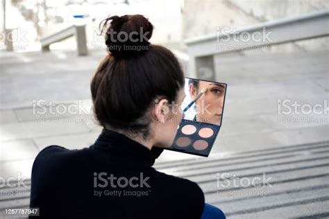 메이크업 브러쉬를 사용하는 동안 야외 에서 계단에 앉아 포니 테일젊은 여성의 뒷모습 20 29세에 대한 스톡 사진 및 기타