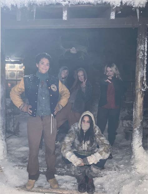 A Group Of People Standing In The Snow With One Person Wearing A Fur